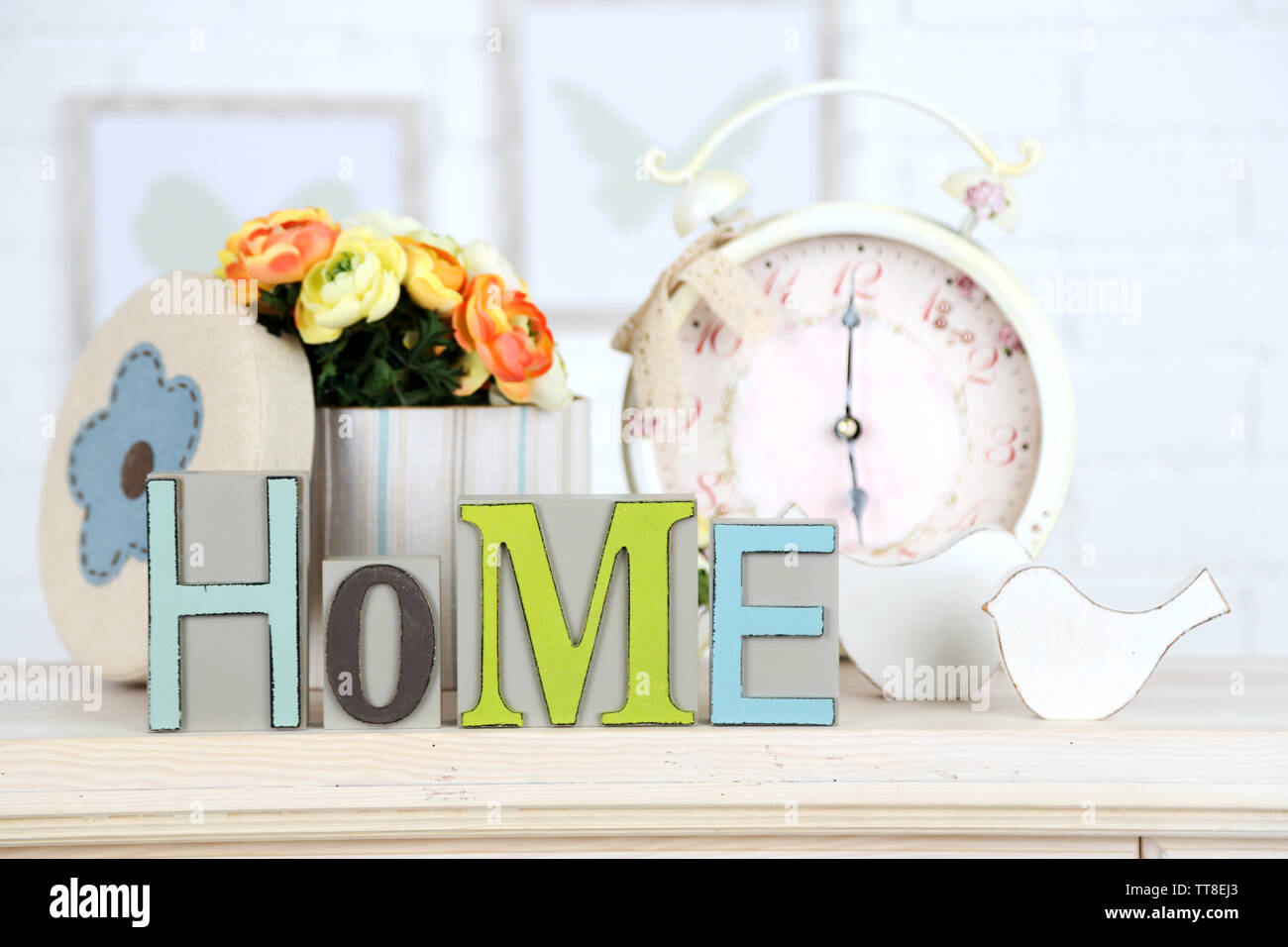 Home in colorful letters, in light white interior, on wooden shelf ...