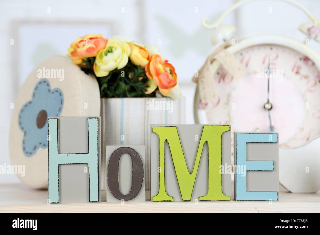 Home in colorful letters, in light white interior, on wooden shelf ...