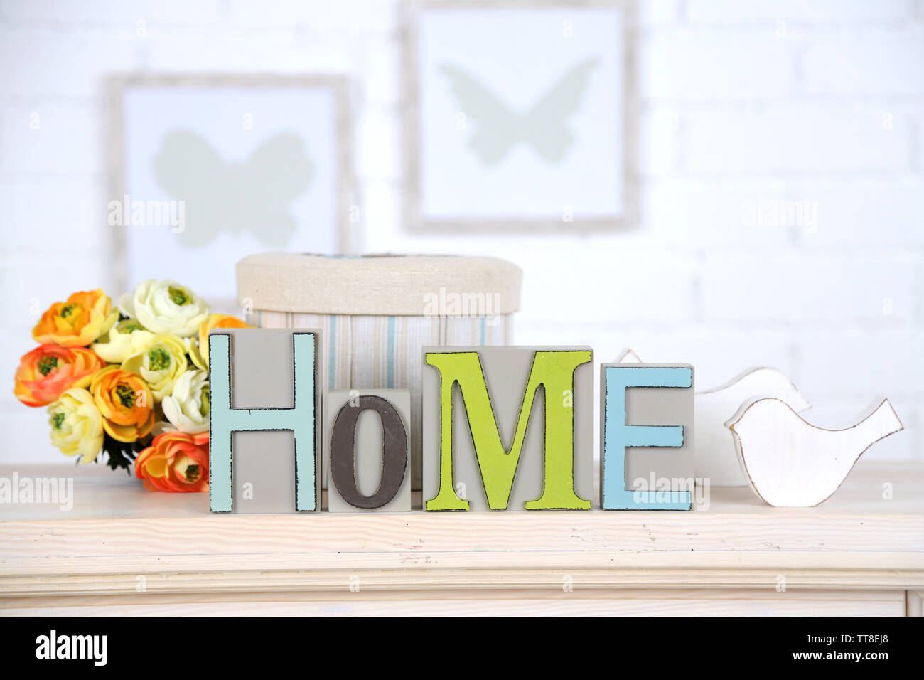 Home in colorful letters, in light white interior, on wooden shelf ...