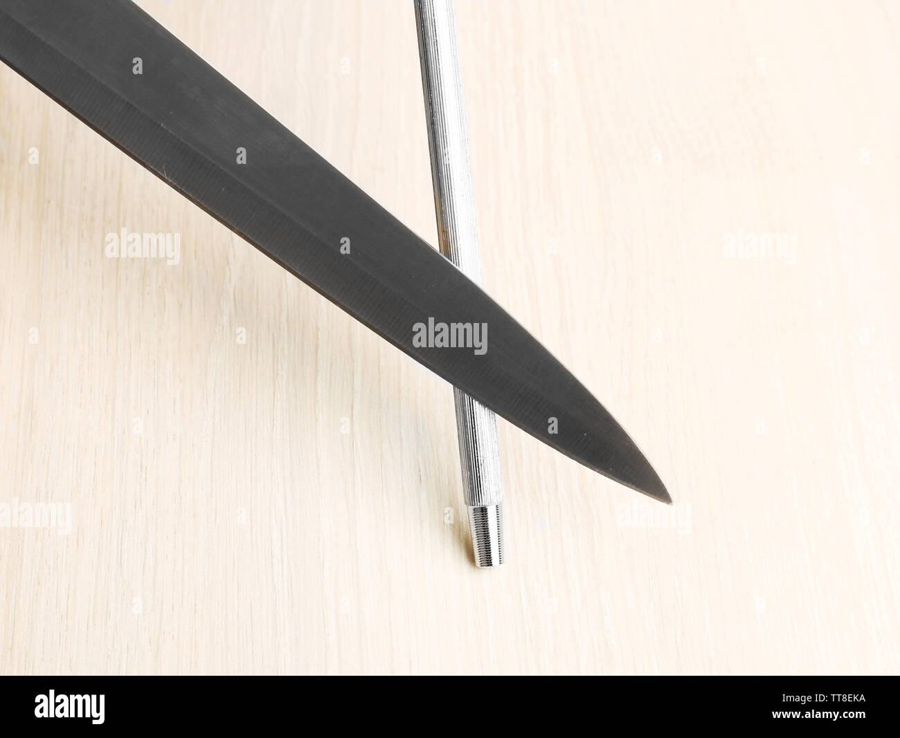 Sharpening knife process on wooden background Stock Photo - Alamy