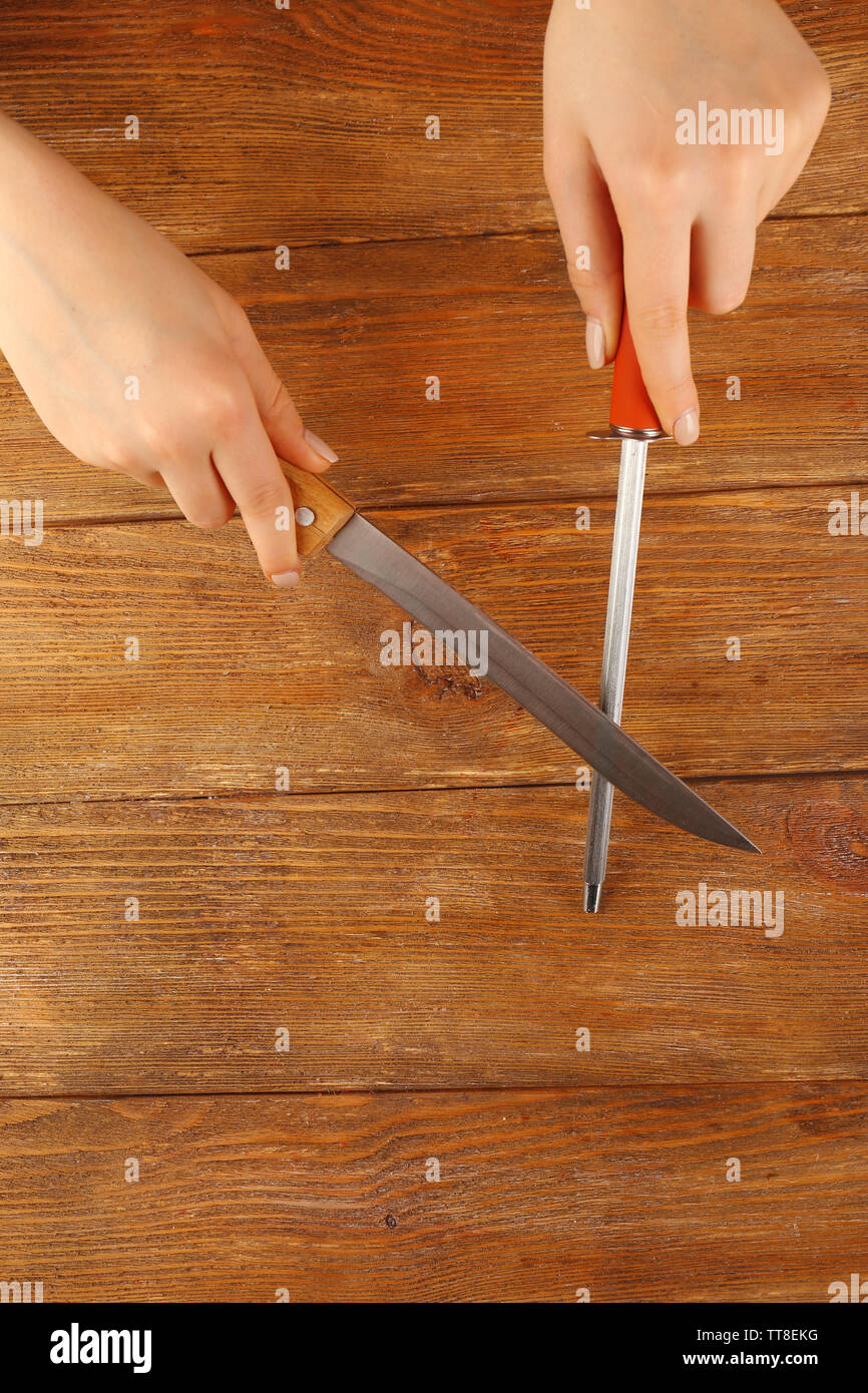 Sharpening knife process on wooden background Stock Photo - Alamy