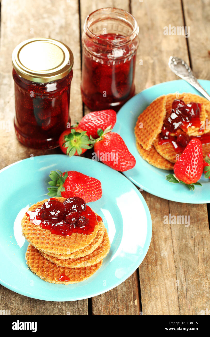 Wafers with strawberry jam and berries on plates on table close up ...