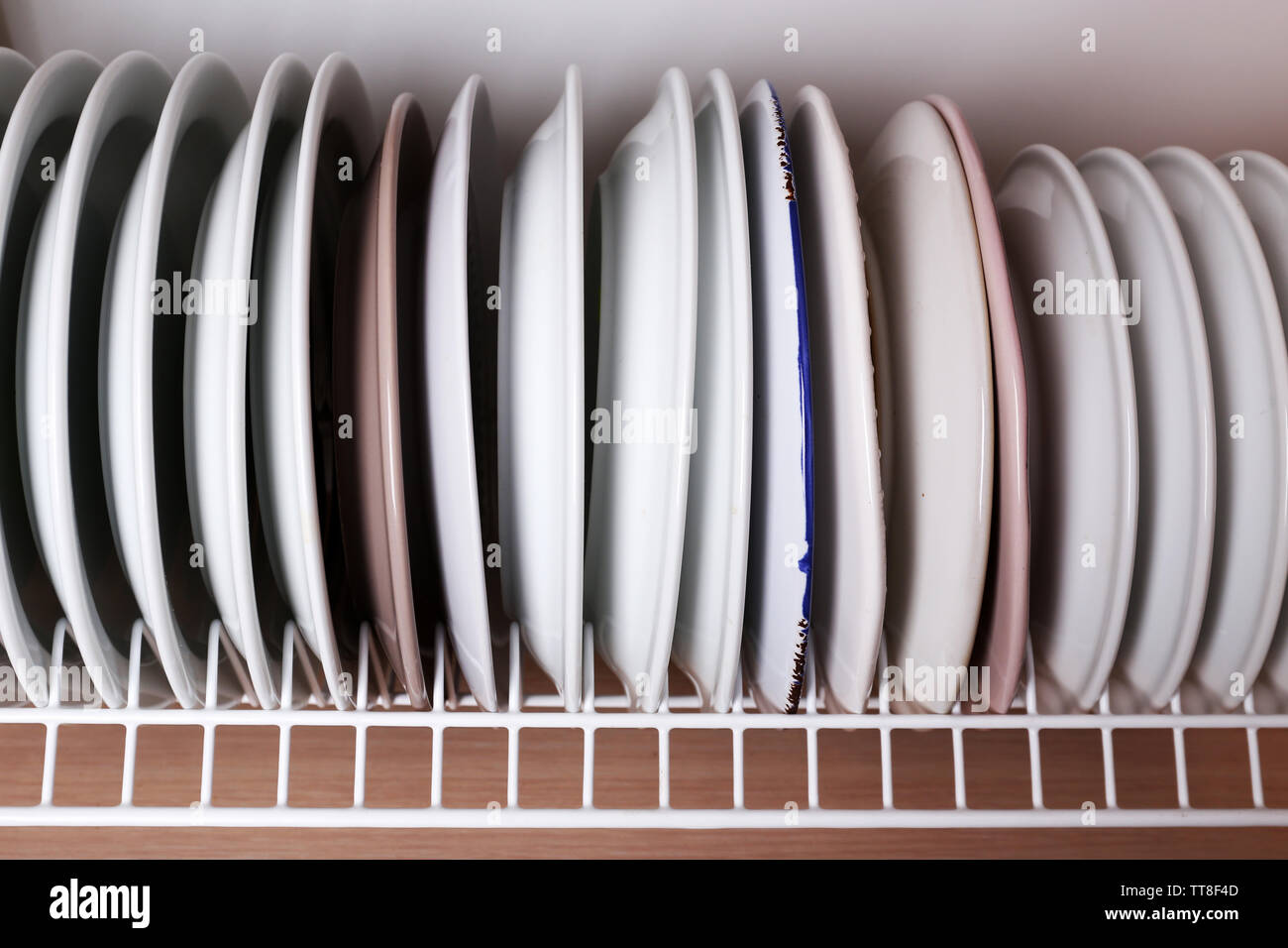 Clean plates drying on metal dish rack on shelf Stock Photo - Alamy