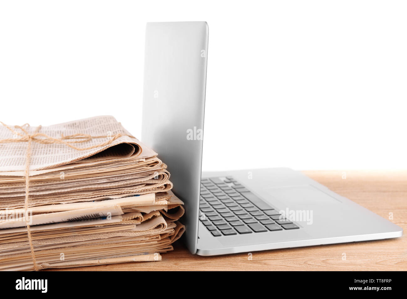 Laptop with stack of newspapers on table isolated on white Stock Photo ...