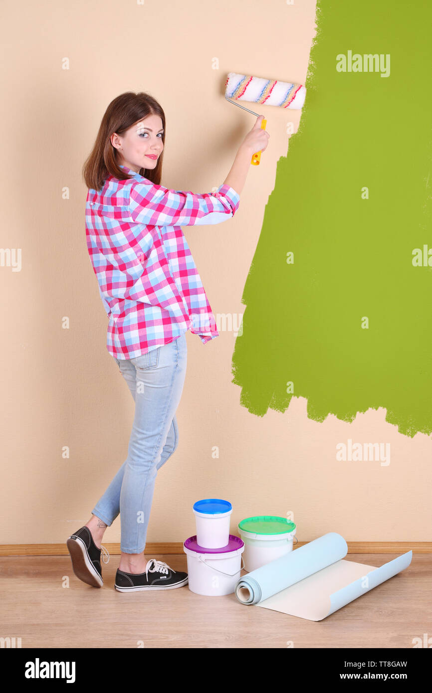 Beautiful woman paints wall in room Stock Photo - Alamy