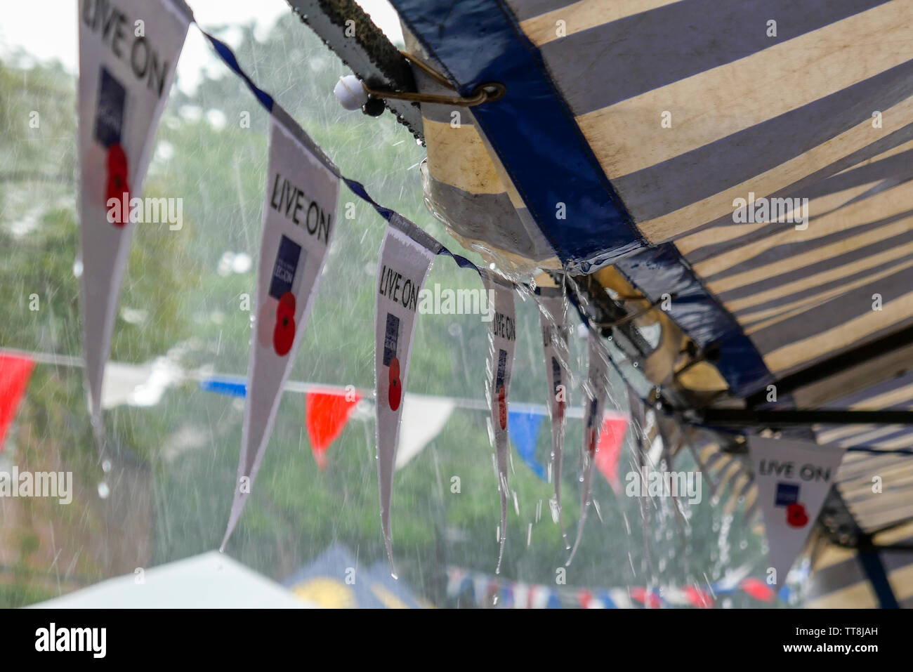 At a village fair bunting and a striped awning is dripping in a heavy ...