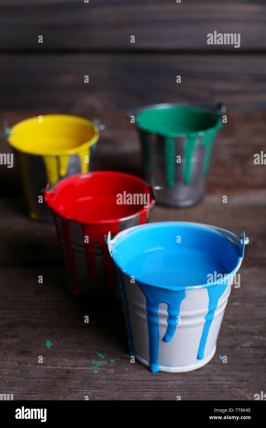 Metal buckets with colorful paint on wooden background Stock Photo - Alamy