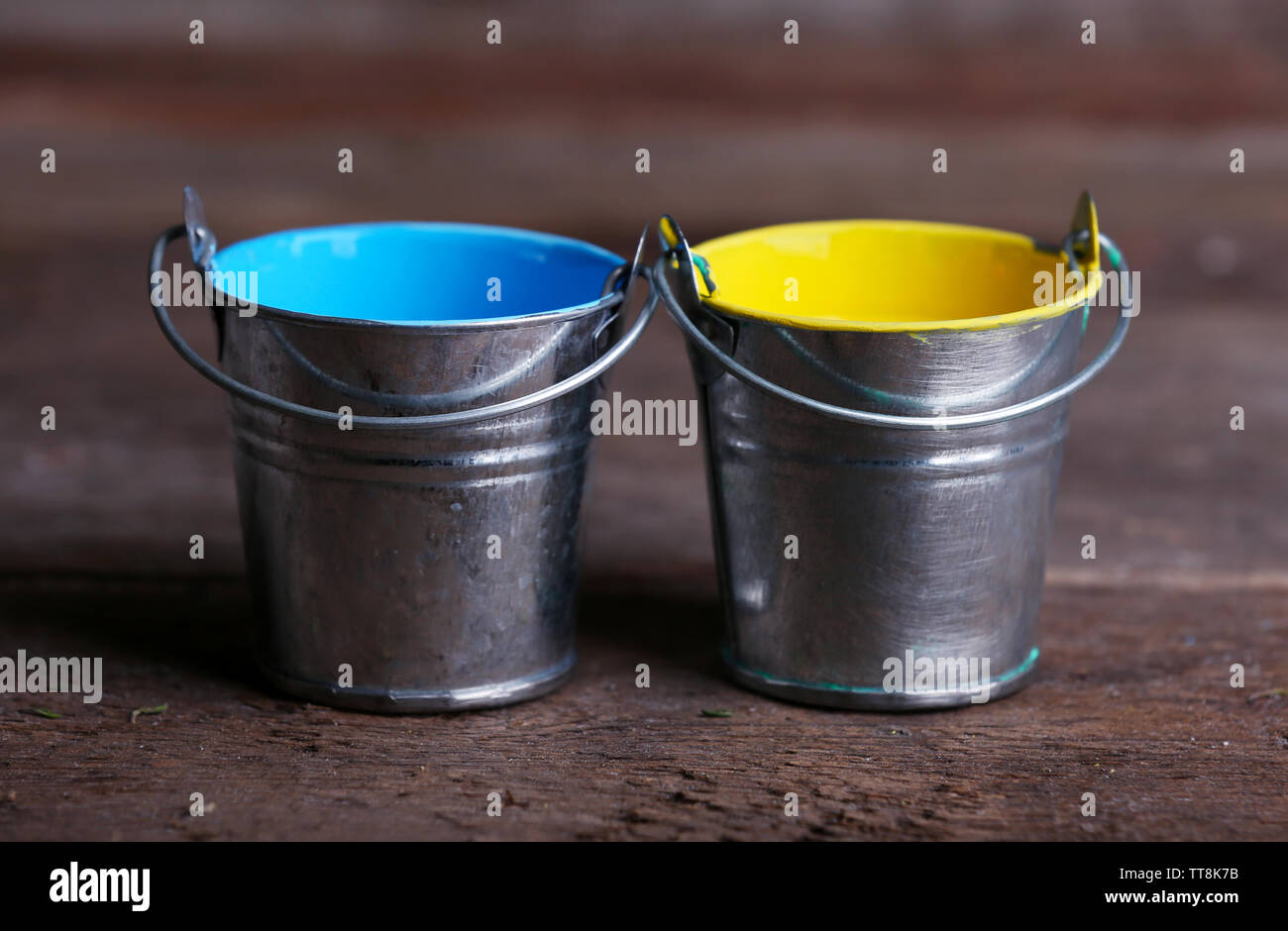 Metal buckets with colorful paint on wooden background Stock Photo - Alamy