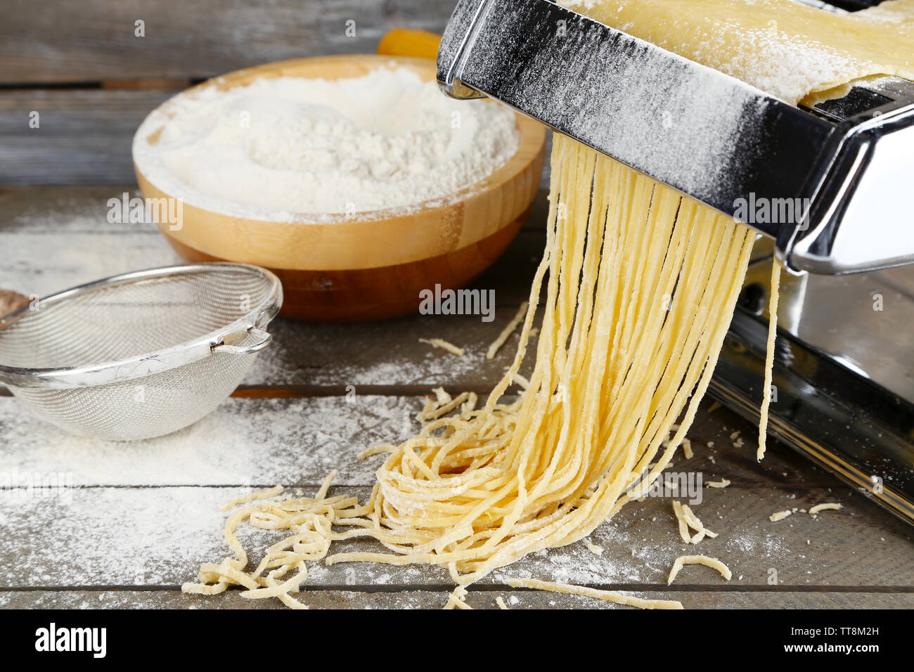 Making vermicelli with pasta machine on wooden background Stock Photo ...