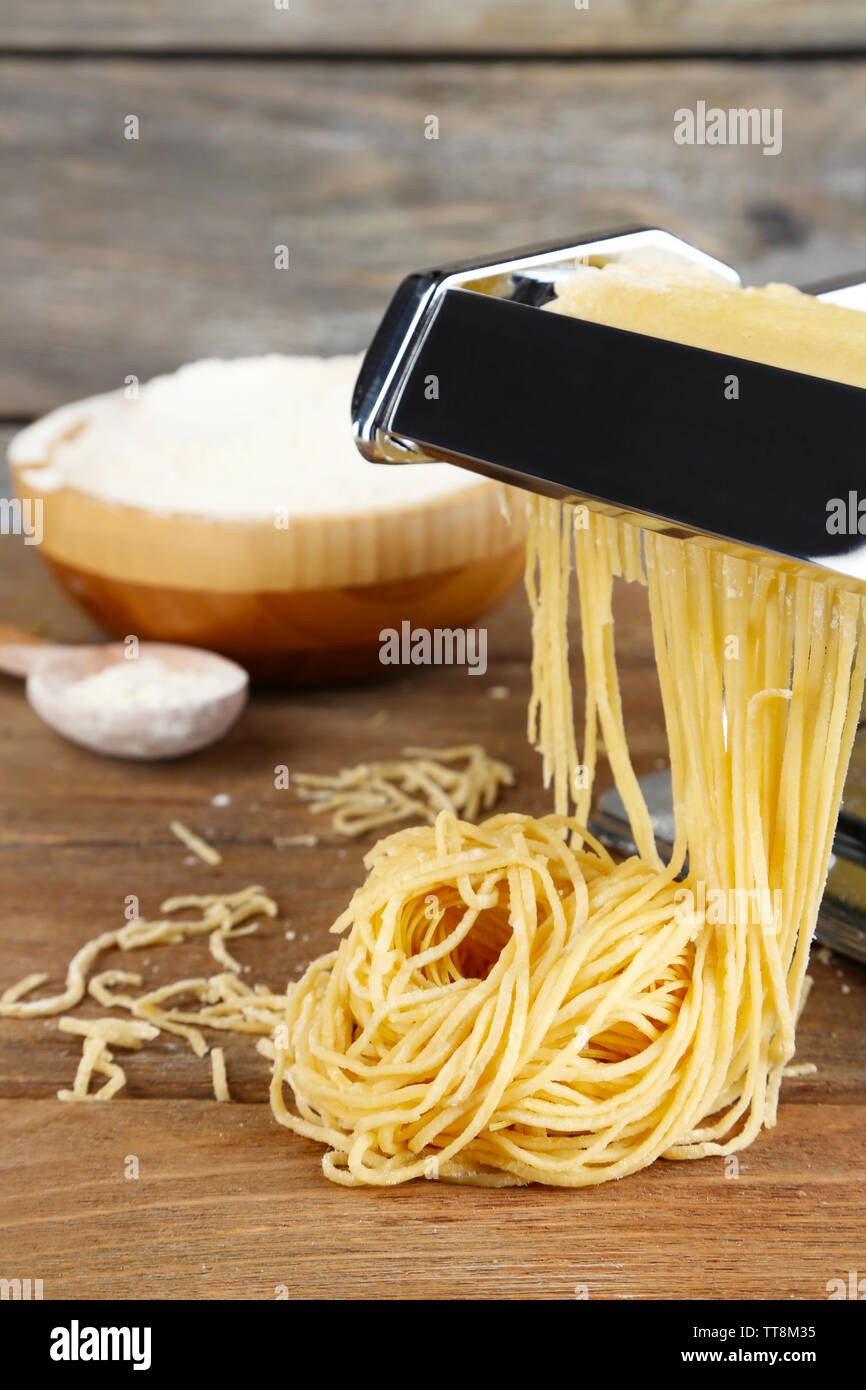 Making vermicelli with pasta machine on wooden background Stock Photo ...