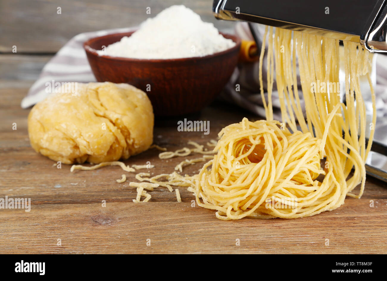 Making vermicelli with pasta machine on wooden background Stock Photo ...