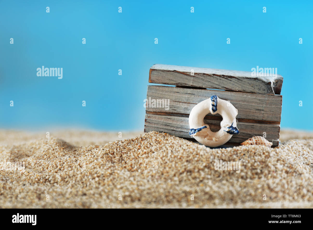 Wooden box with lifebuoy on sand on blue background Stock Photo - Alamy