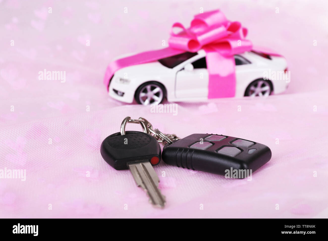 Keys and car with bow as present on pink background Stock Photo - Alamy