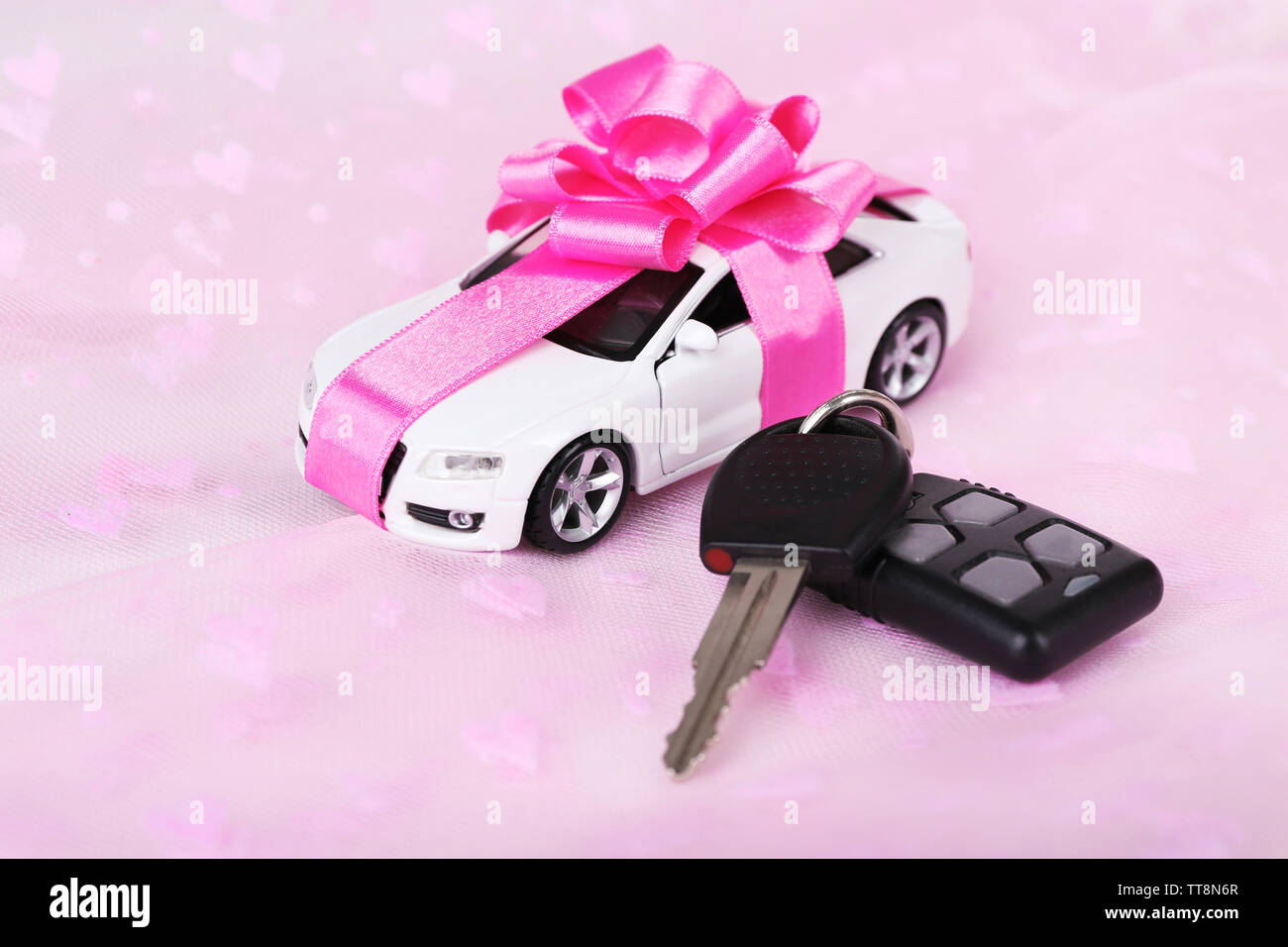 Keys and car with bow as present on pink background Stock Photo - Alamy
