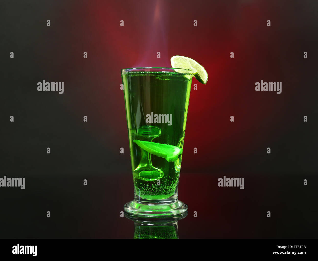 Flaming green cocktail on colorful background Stock Photo - Alamy