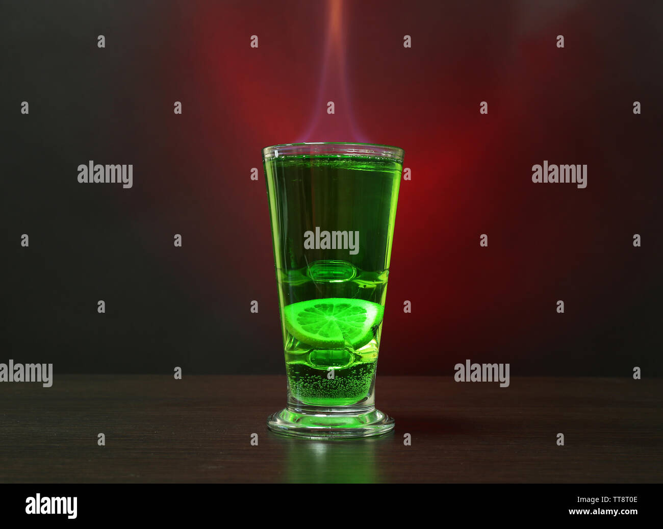Flaming green cocktail on colorful background Stock Photo - Alamy