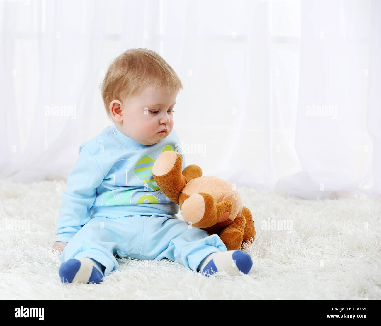Cute baby boy with teddy bear on carpet, on light background Stock ...