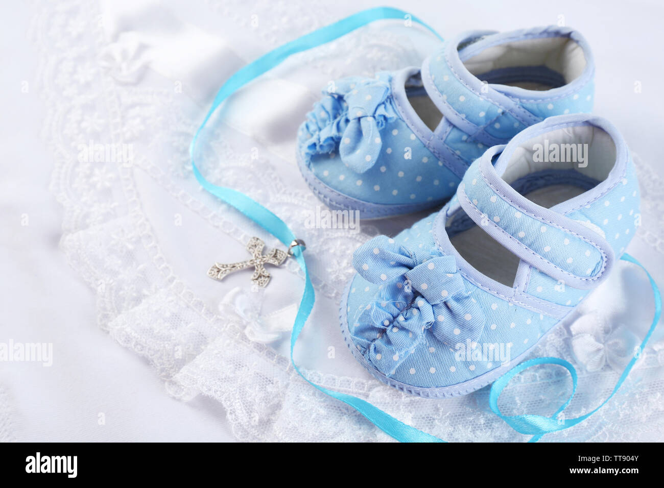 Baby shoe and cross for Christening Stock Photo - Alamy