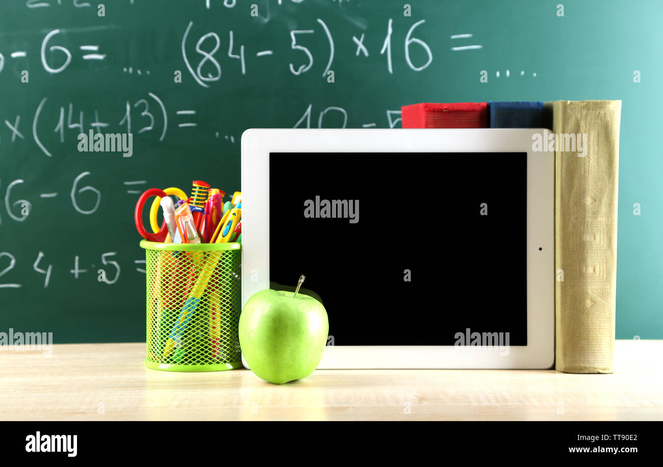 Digital tablet, books, colorful pens and apple on desk in front of ...