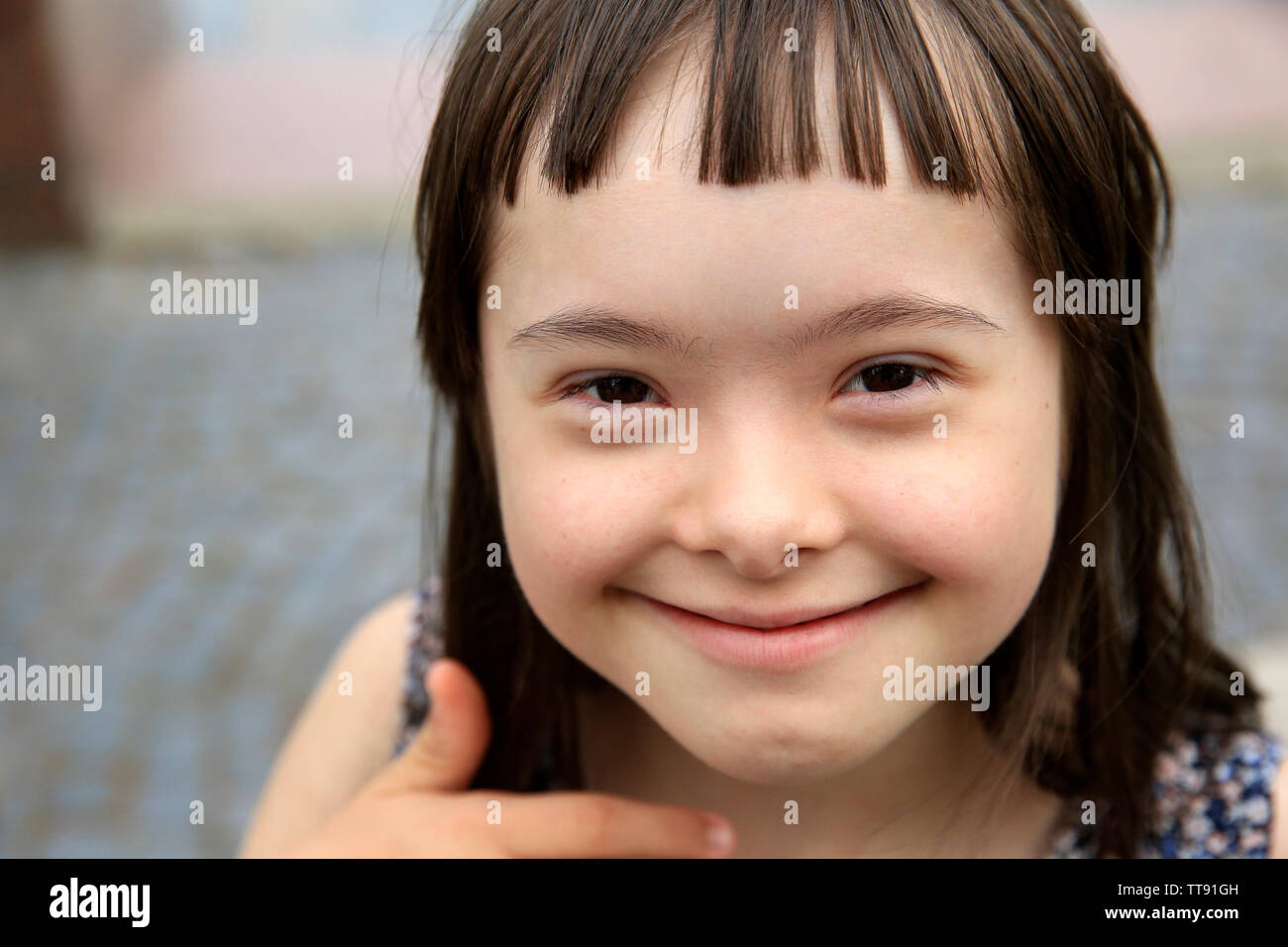 Cute smiling down syndrome girl on the blue background Stock Photo - Alamy