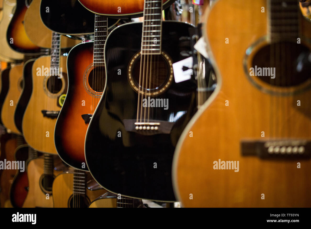metal string acoustic guitars hanging on the walls of music store ready ...
