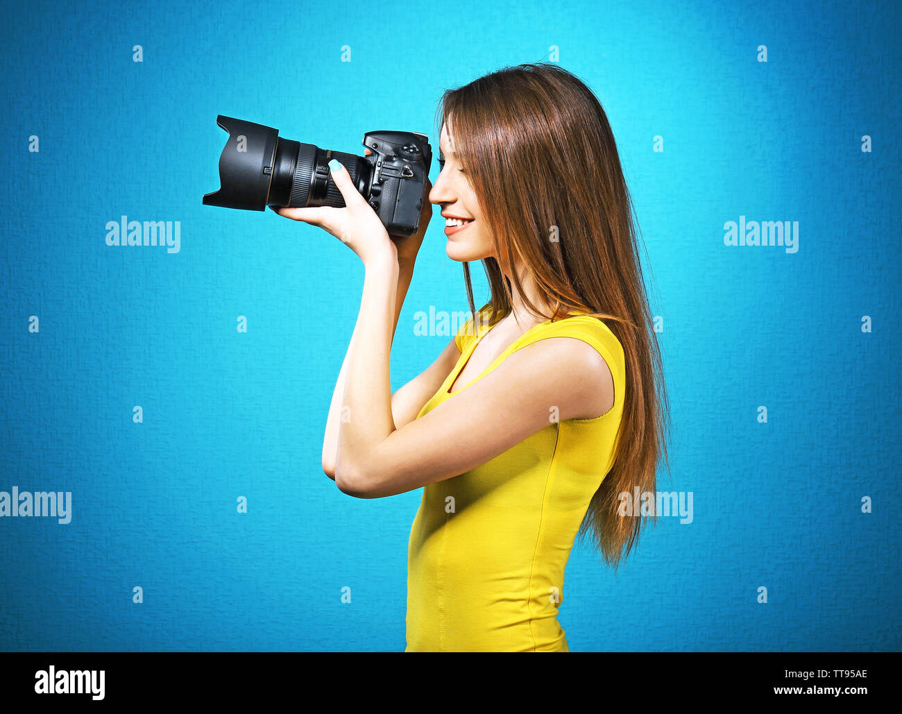 Young female photographer taking photos on blue background Stock Photo ...