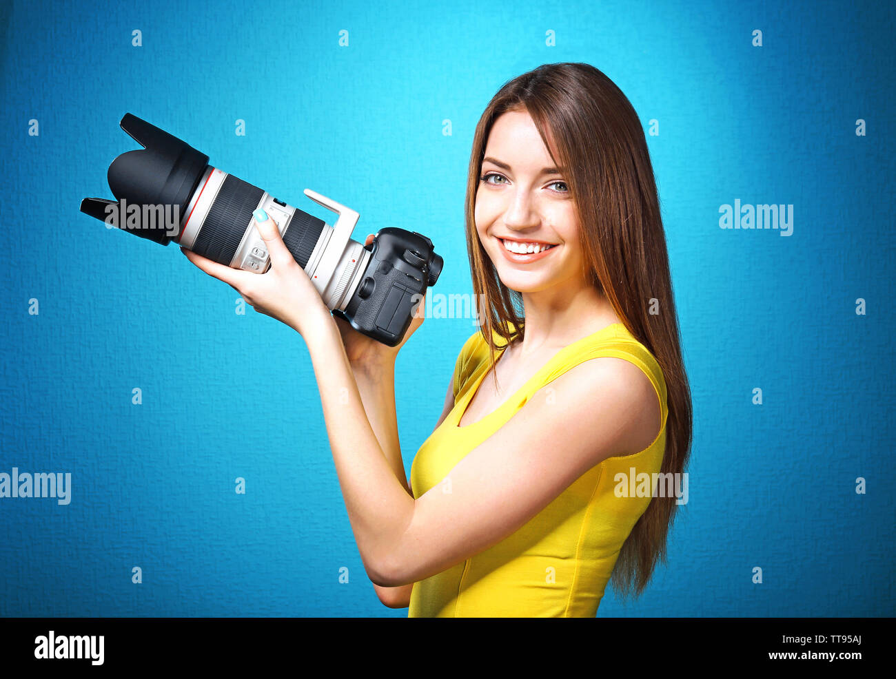 Young female photographer taking photos on blue background Stock Photo ...