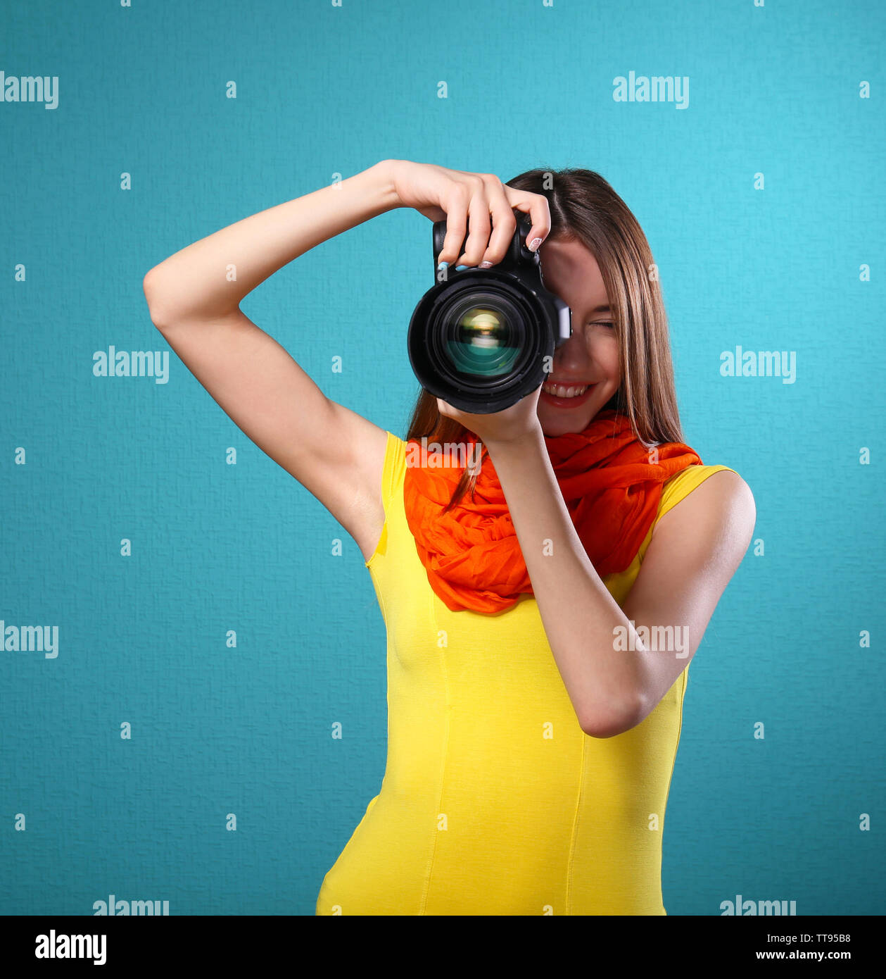 Young female photographer taking photos on blue background Stock Photo ...