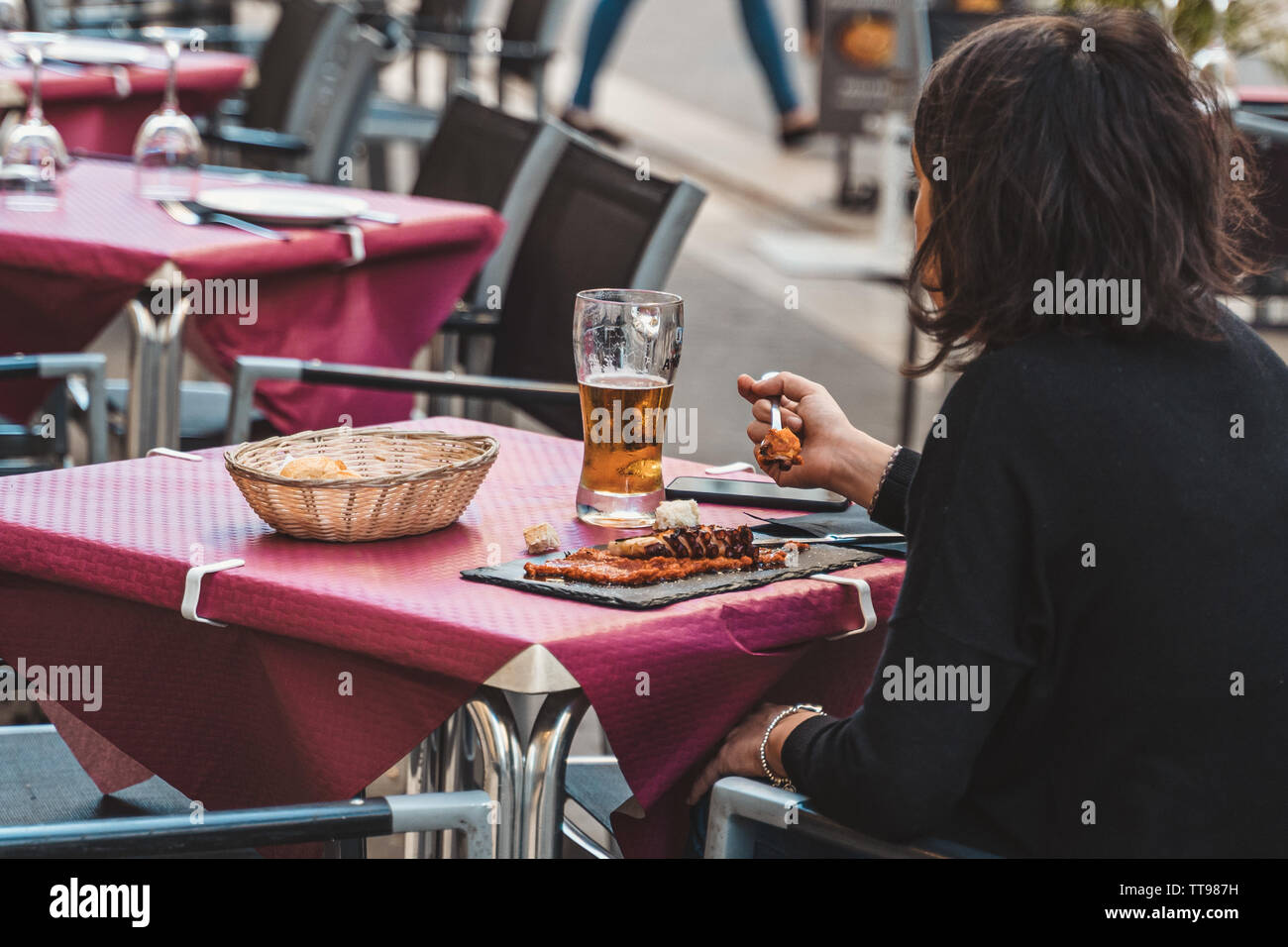 Woman eating octopus and drinking beer at the terrace. Spanish seafood ...