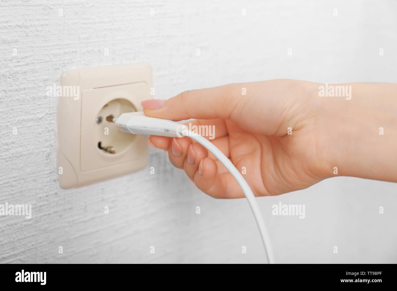 Hand putting plug in electricity socket close up Stock Photo - Alamy