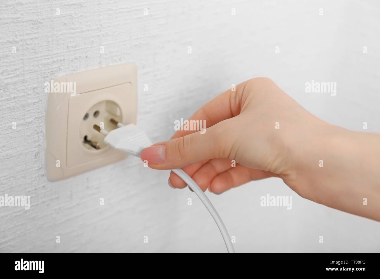Hand putting plug in electricity socket close up Stock Photo - Alamy