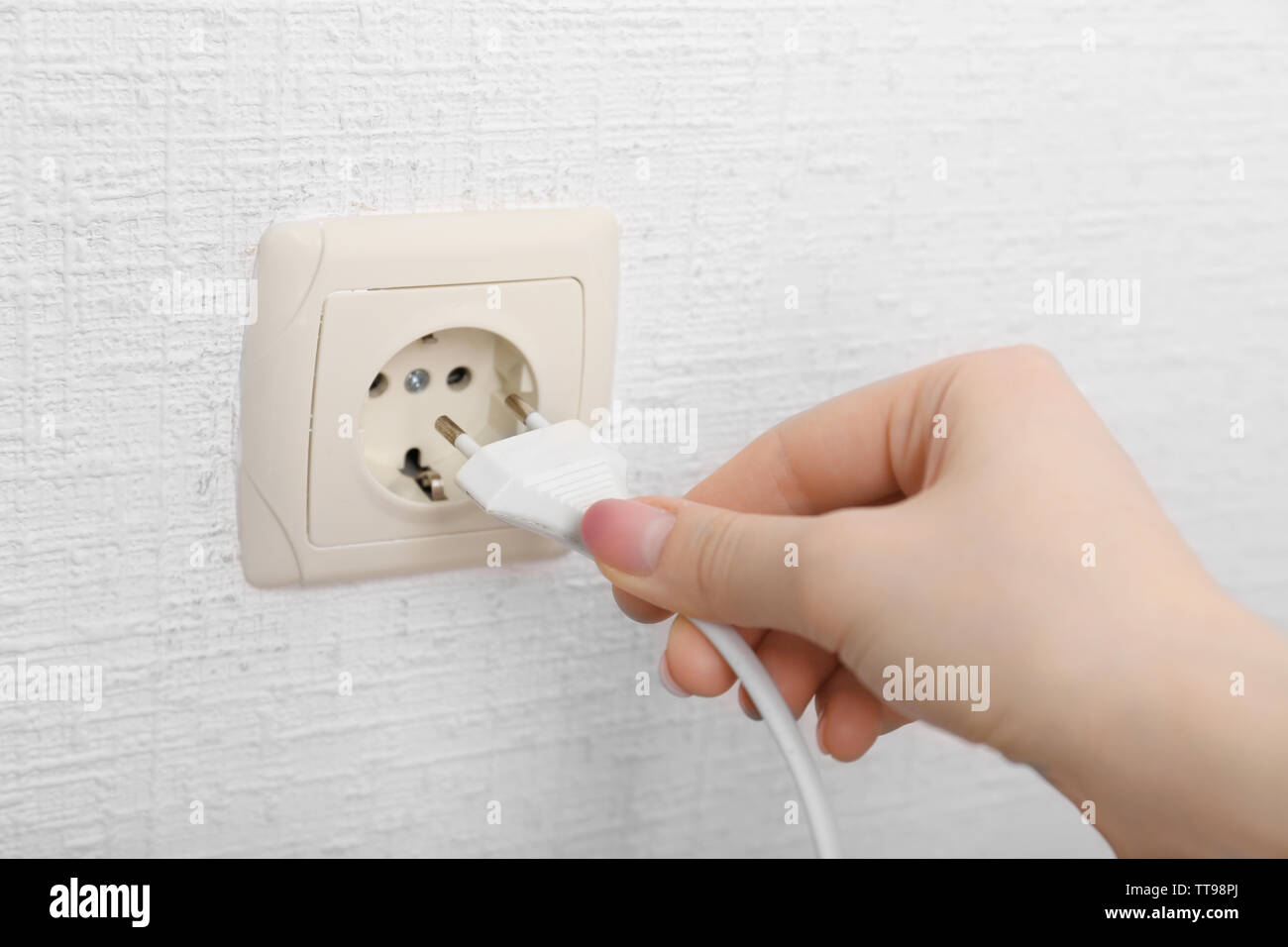 Hand putting plug in electricity socket close up Stock Photo - Alamy