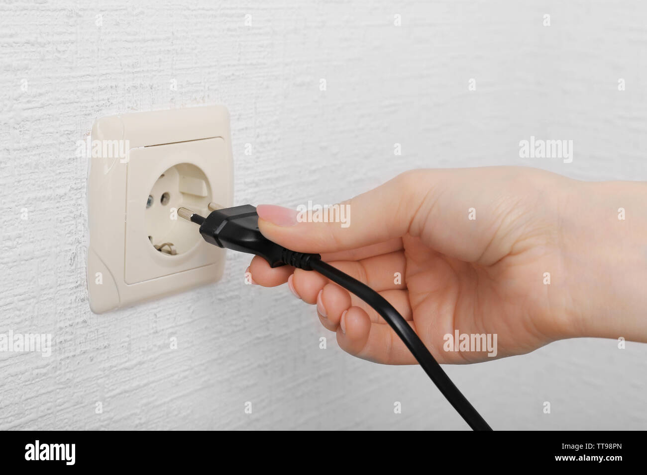 Hand putting plug in electricity socket close up Stock Photo - Alamy