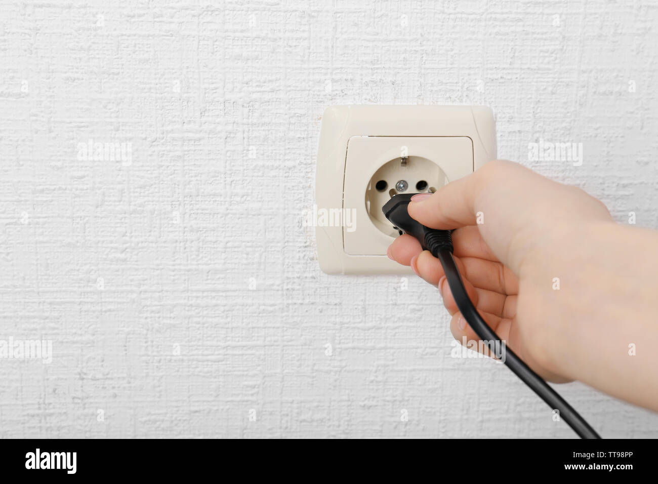 Hand putting plug in electricity socket close up Stock Photo - Alamy