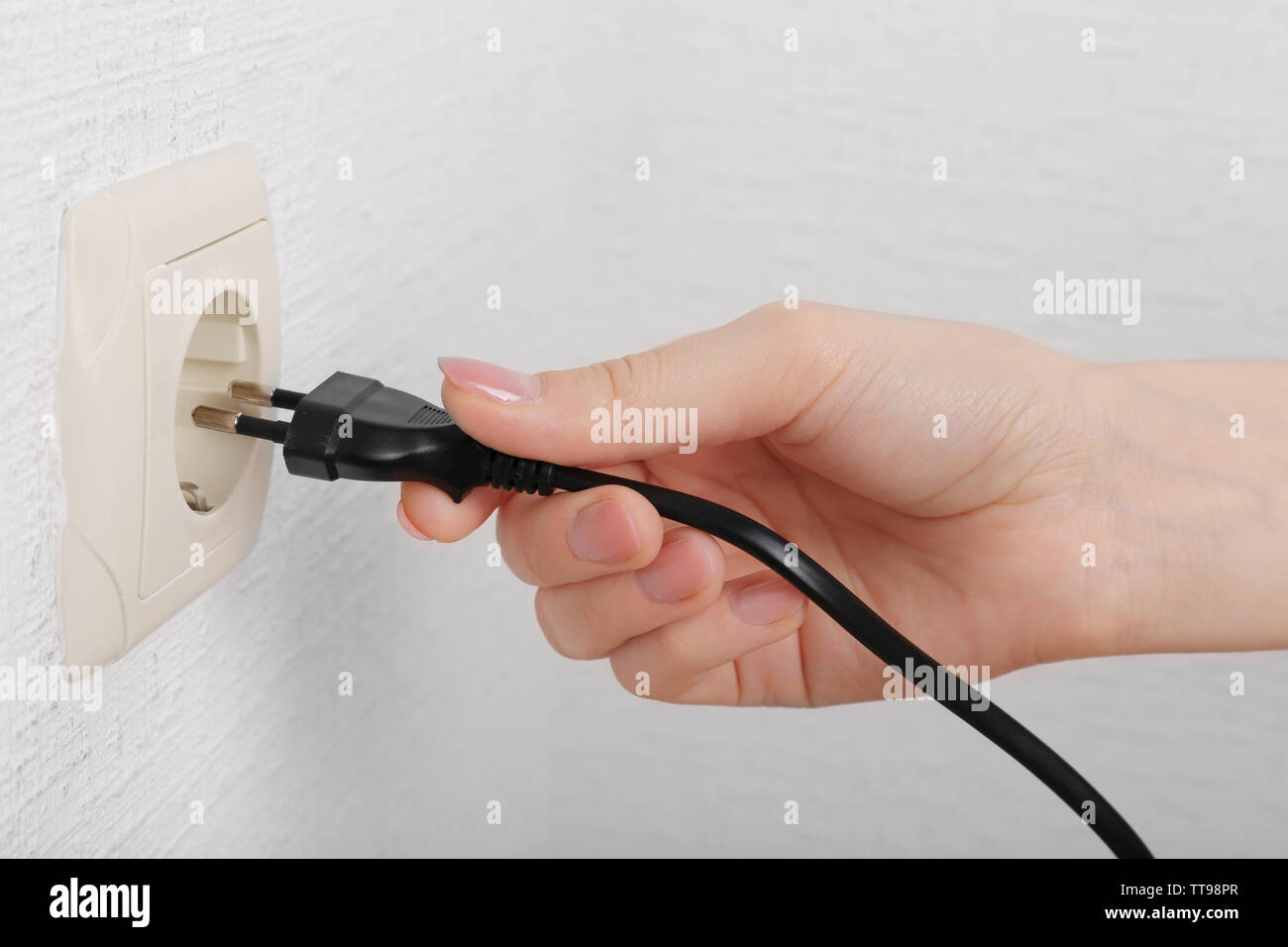 Hand putting plug in electricity socket close up Stock Photo - Alamy