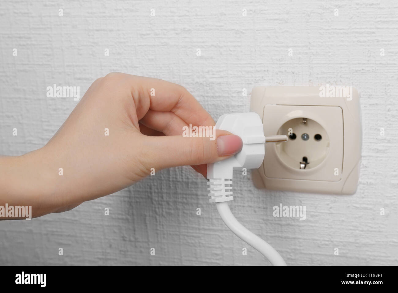 Hand putting plug in electricity socket close up Stock Photo - Alamy