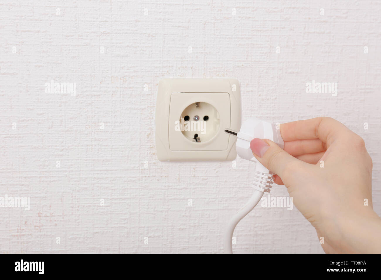 Hand putting plug in electricity socket close up Stock Photo - Alamy