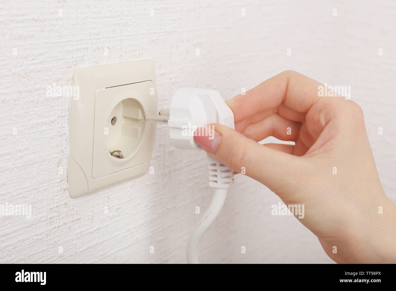 Hand putting plug in electricity socket close up Stock Photo - Alamy