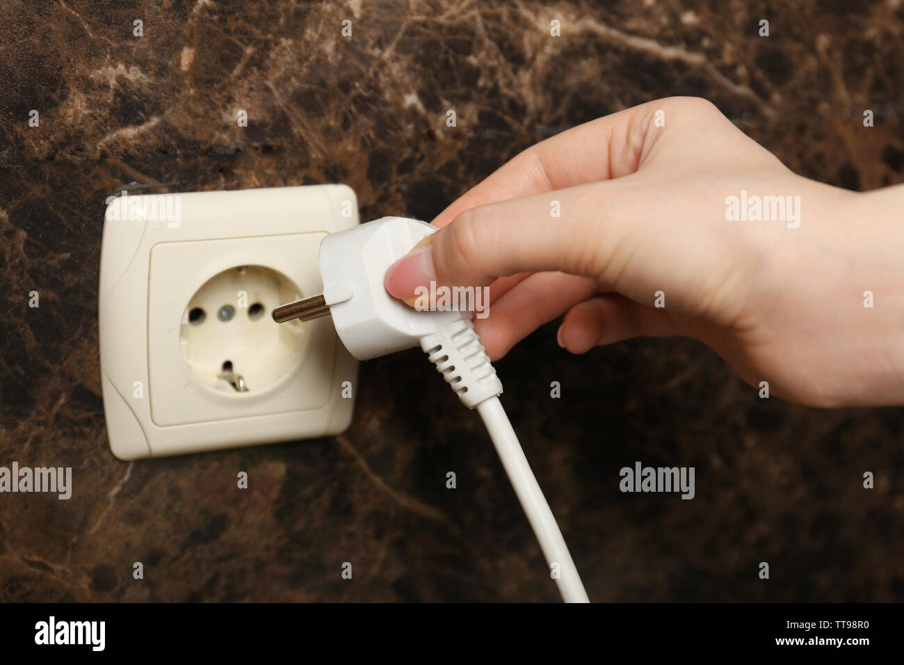 Hand putting plug in electricity socket close up Stock Photo - Alamy