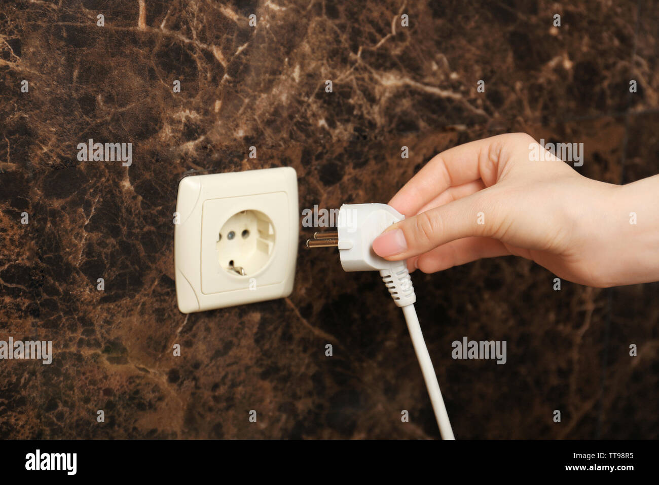 Hand putting plug in electricity socket close up Stock Photo - Alamy