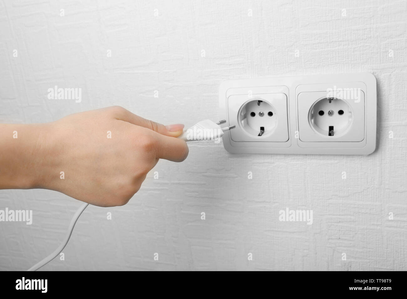 Hand putting plug in electricity socket close up Stock Photo - Alamy