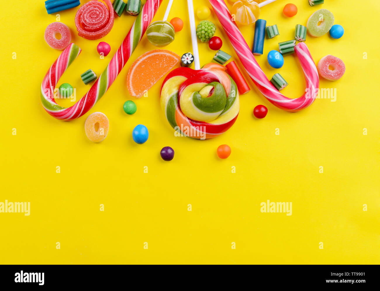 Colorful candies on yellow background Stock Photo - Alamy