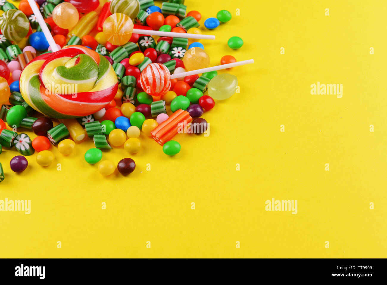 Colorful candies on yellow background Stock Photo - Alamy