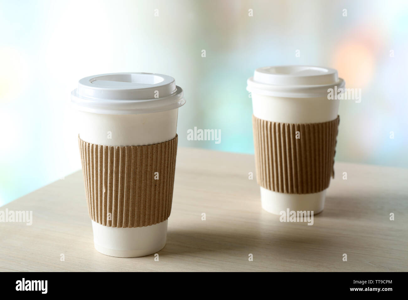 Paper cups of coffee on table on bright background Stock Photo - Alamy