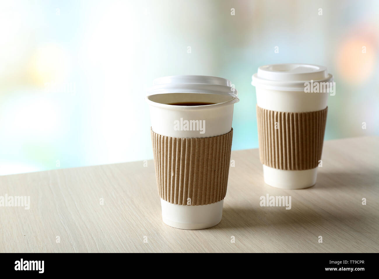 Paper cups of coffee on table on bright background Stock Photo - Alamy