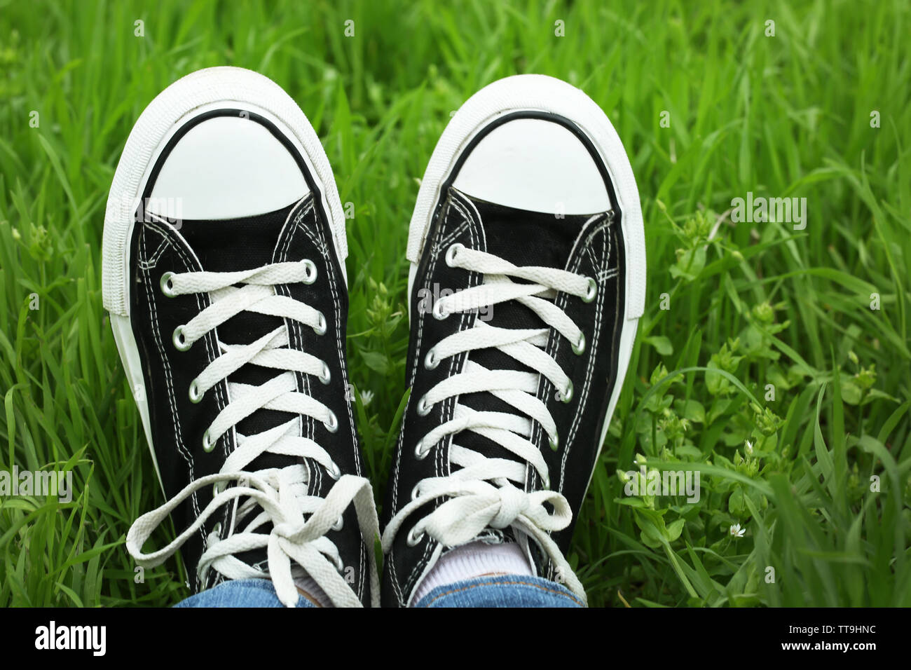 Female feet in gumshoes on green grass background Stock Photo - Alamy