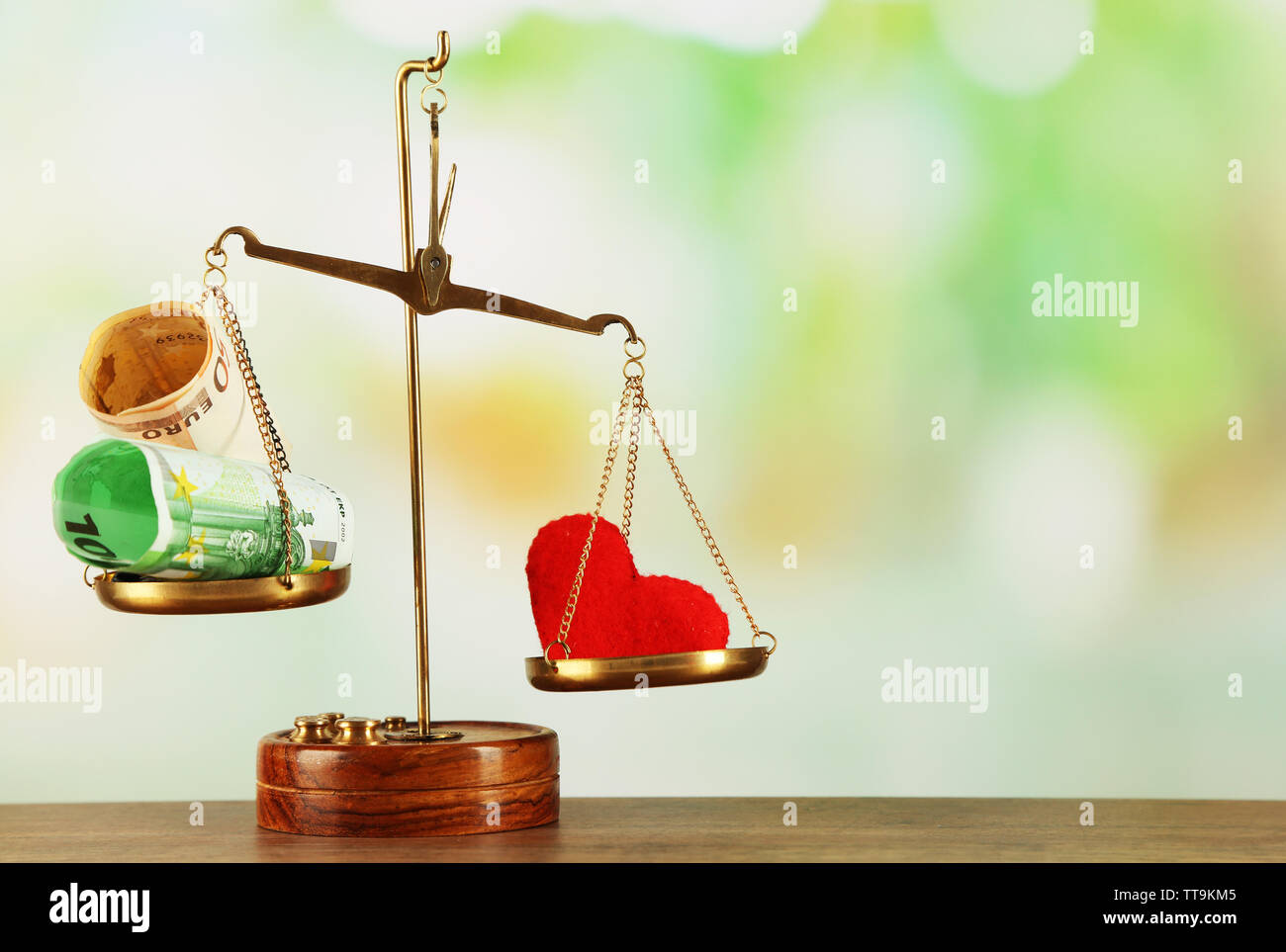 Money and heart in balance scales on light blurred background Stock ...