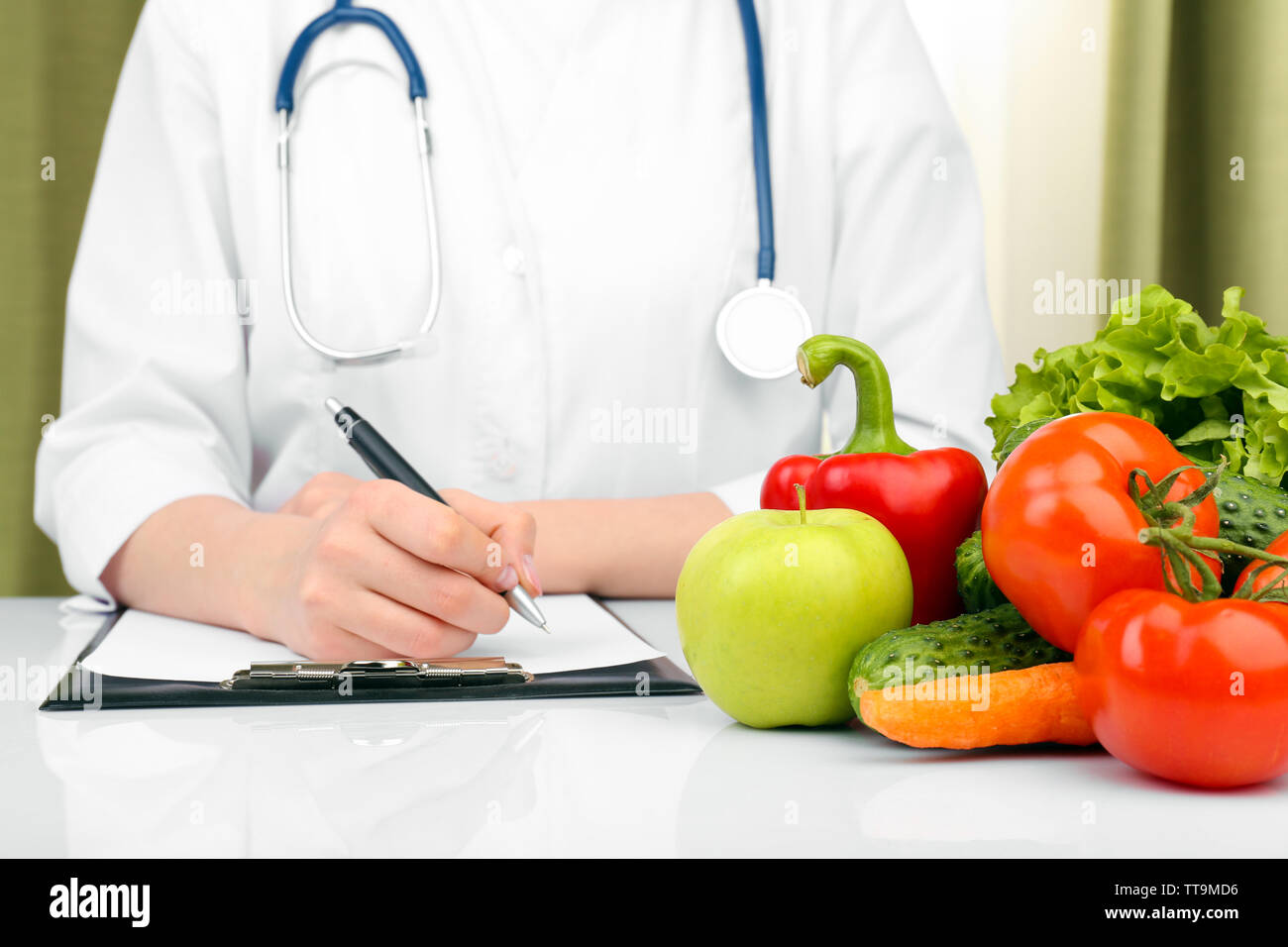 Nutritionist doctor writing diet plan in office Stock Photo - Alamy