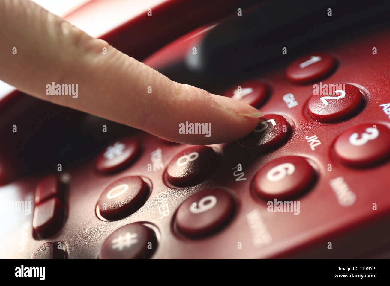 Finger pressing number button on telephone to make a call, close up ...