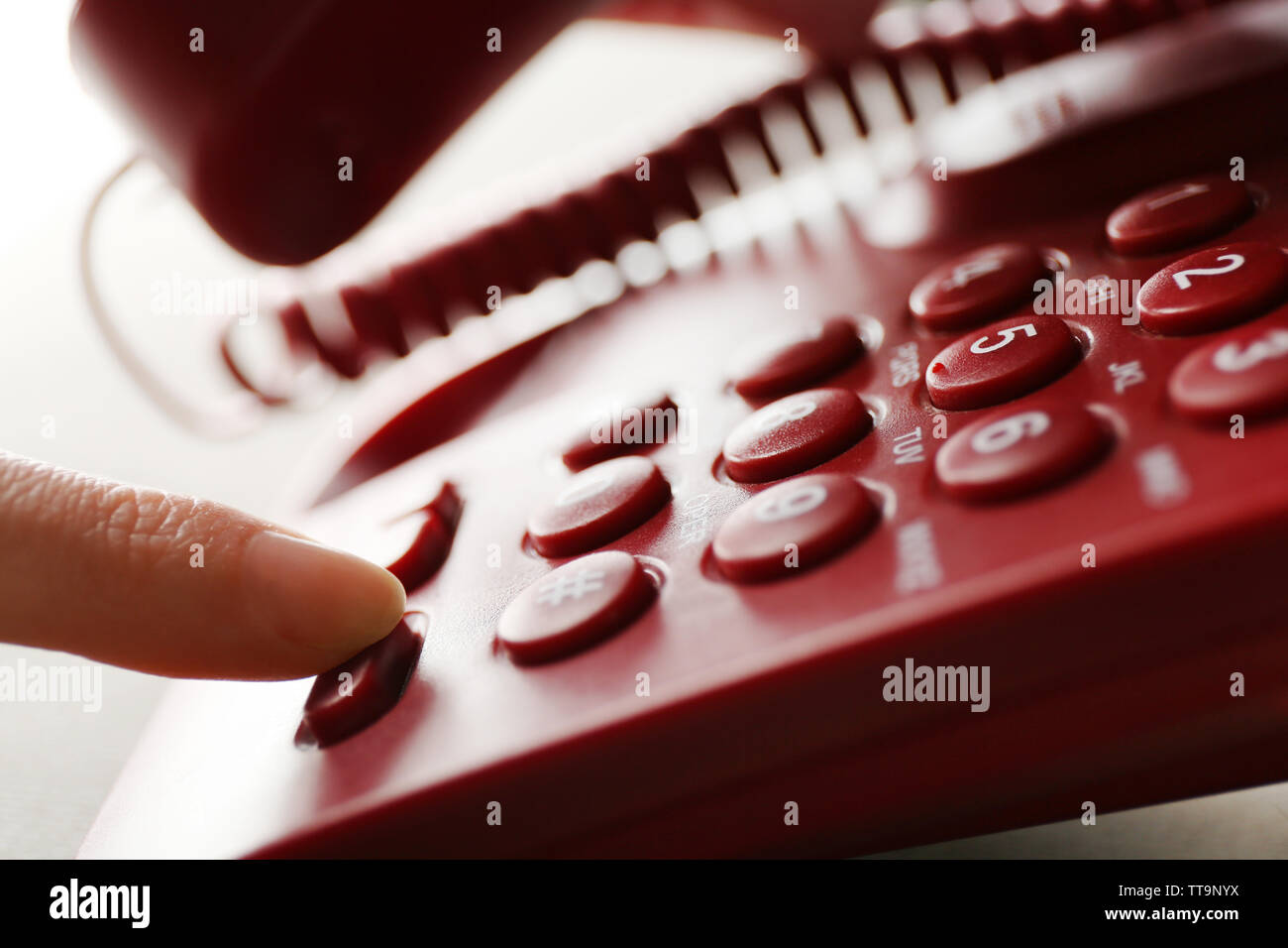Finger pressing number button on telephone to make a call, close up ...